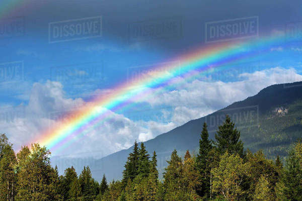 Colourful Rainbow Across The Sky With Mountain Side, Storm Clouds And ...