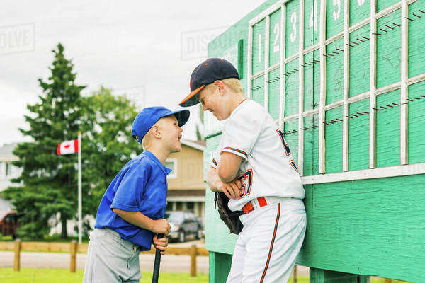 Two boys in baseball uniforms playfully argue in front of the ...