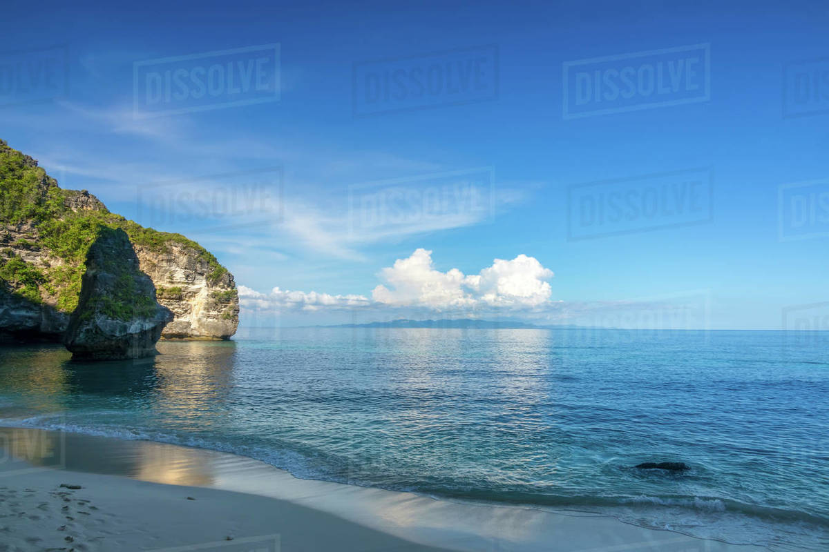 Tropical beach and cliffs overgrown with shrubs. Blue sky and clouds ...