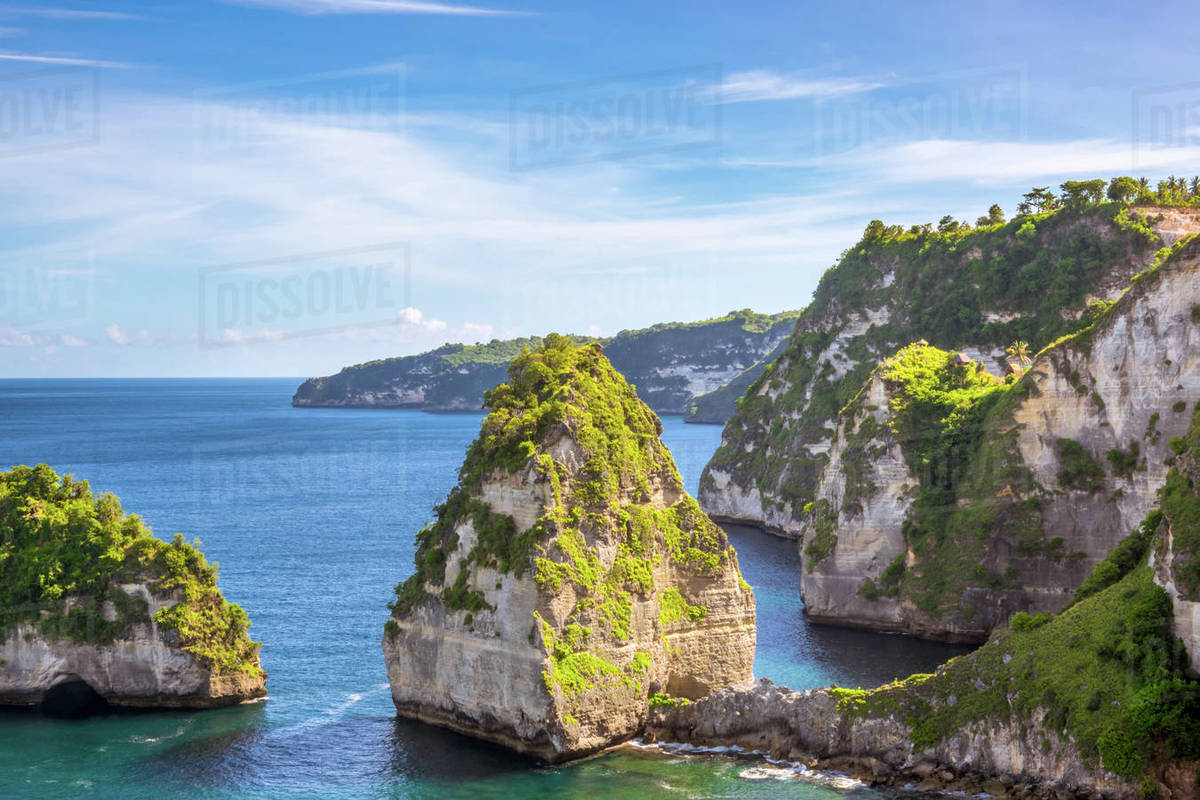 Indonesia. The ocean shore of a rocky island. A few huts on top of a ...