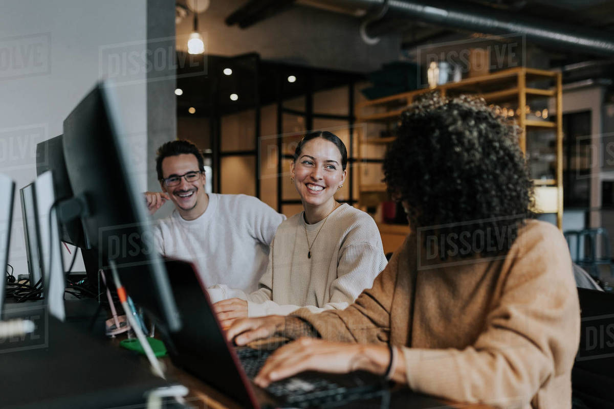 Female computer programmer discussing strategy with happy colleagues at ...