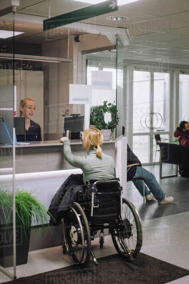 Female patient sitting on wheelchair and doing inquiry with ...