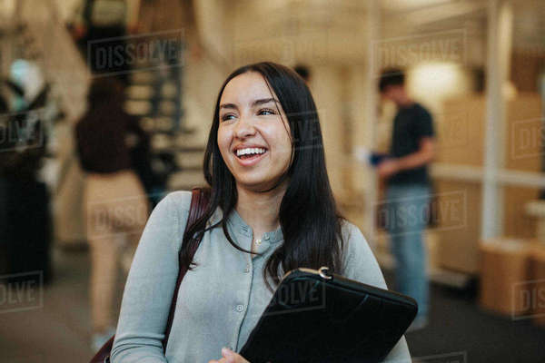 Cheerful female student carrying file folder at university - Royalty ...