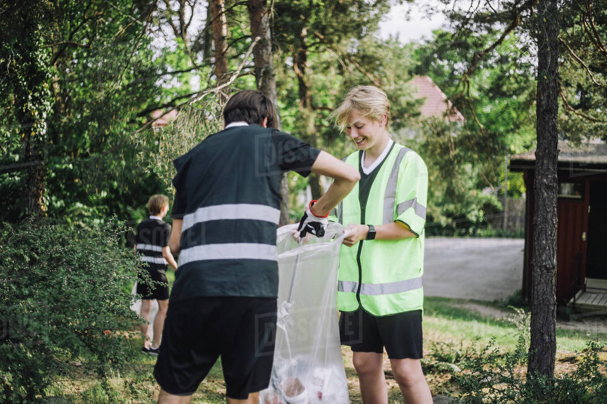 Happy soccer boys collecting plastic in garbage bag - Royalty-free ...