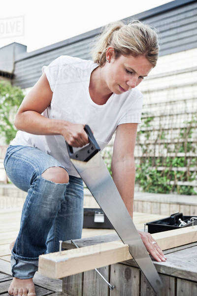 Woman sawing wood with saw - Royalty-free Stock Photo | Dissolve