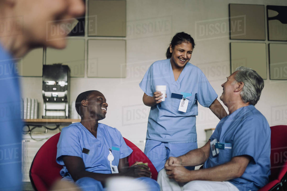 Happy multiracial doctors talking in cafeteria of hospital during ...