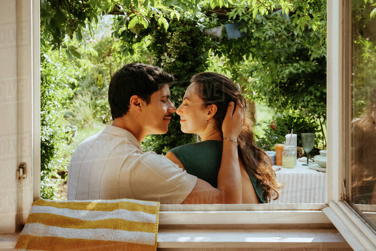 Romantic young couple kissing each other seen through window - Royalty ...