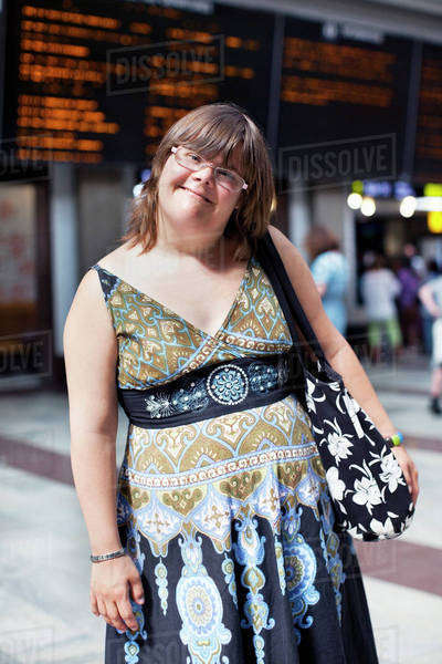 Portrait of smiling woman with down syndrome standing with handbag at ...