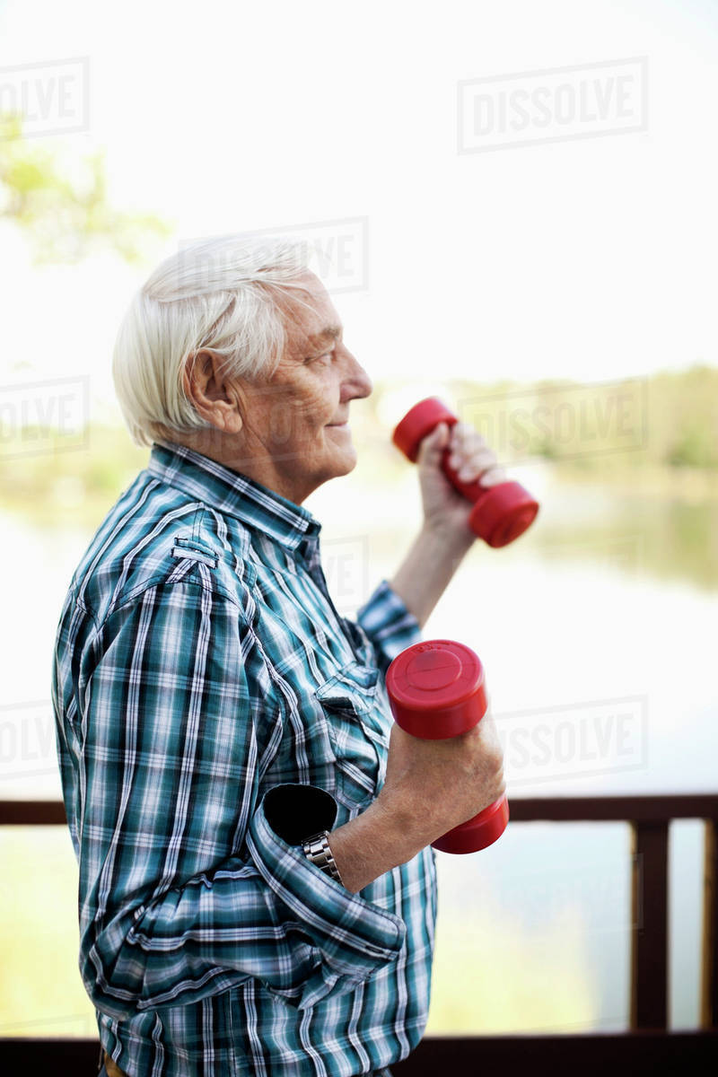 Side view of senior adult man lifting hand weight outdoors - Royalty ...