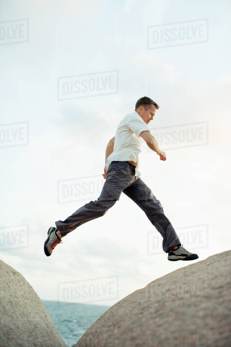 Full length of man jumping over rocks - Stock Photo - Dissolve