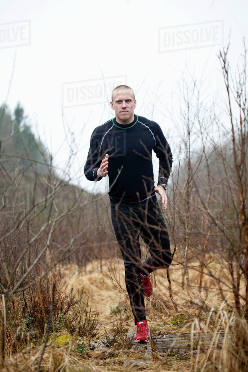 Mid adult man running through woods - Royalty-free Stock Photo | Dissolve