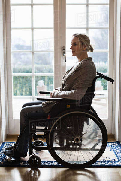 Side view of disabled woman in wheelchair at home - Stock Photo - Dissolve