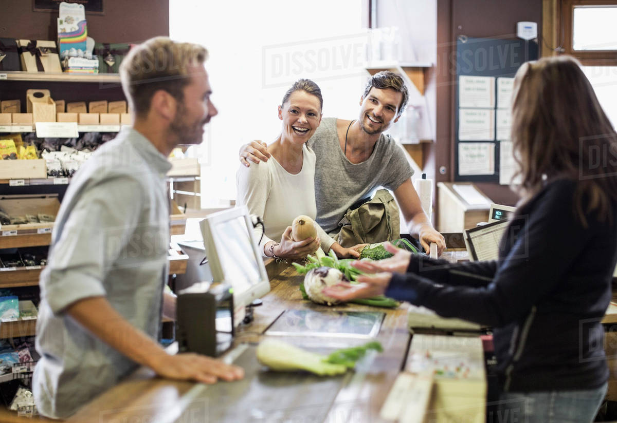 Happy friends with cashier at checkout counter in supermarket - Royalty ...