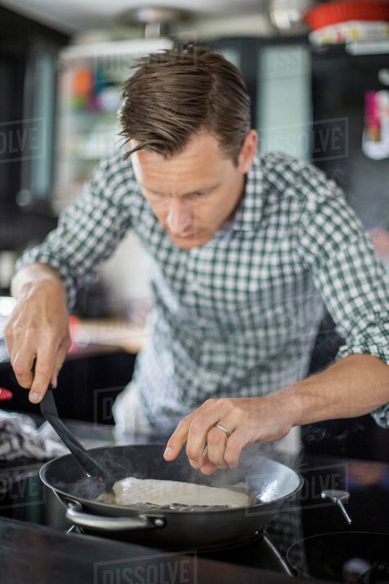 Man cooking fish in kitchen - Royalty-free Stock Photo | Dissolve