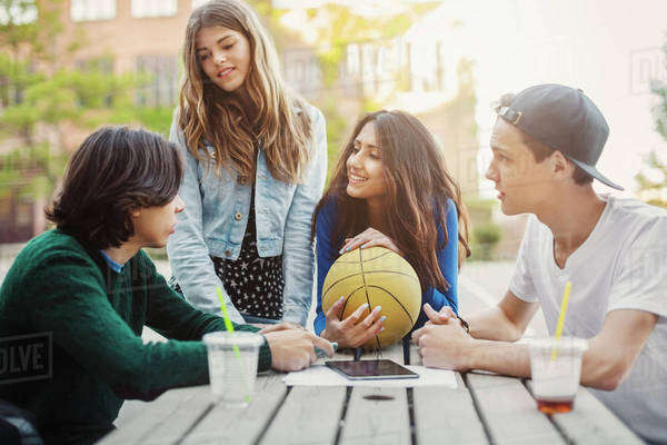 Happy teenagers discussing at table outdoors - Royalty-free Stock Photo ...