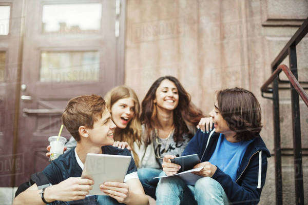 Happy teenagers enjoying on steps outdoors - Stock Photo - Dissolve