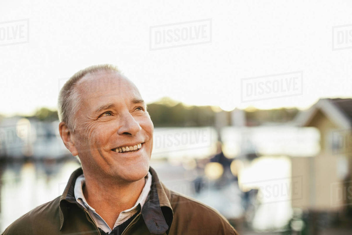 Thoughtful senior man looking up and smiling outdoors - Royalty-free ...