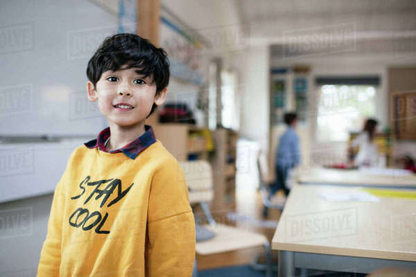 Portrait of boy standing in classroom - Stock Photo - Dissolve