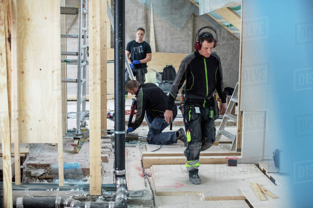 Manual workers working on messy floor at construction site - Royalty ...