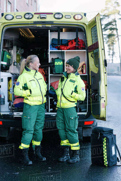 Full length of female paramedics talking while standing outside ...