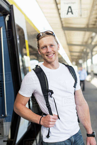 Portrait of happy man standing by metro train at station - Royalty-free ...