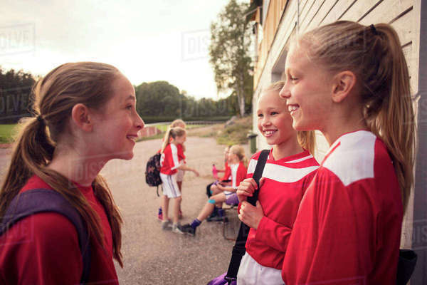 Girls talking against friends by wall - Royalty-free Stock Photo | Dissolve