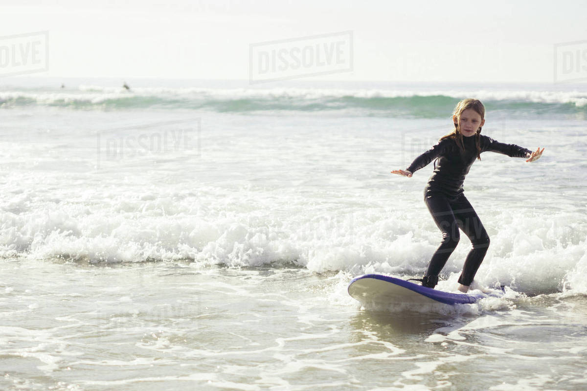 Full length of girl surfing in sea - Stock Photo - Dissolve