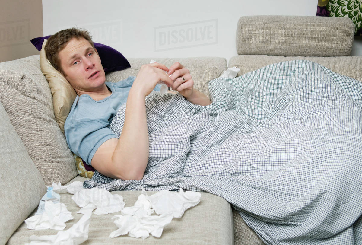Man with cold lying on sofa - Stock Photo - Dissolve