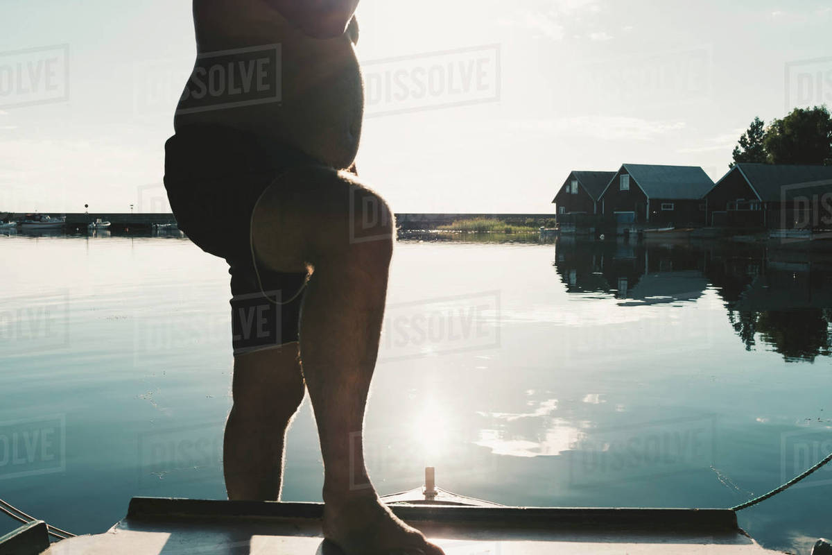 Low section of shirtless man standing on boat by lake - Royalty-free ...