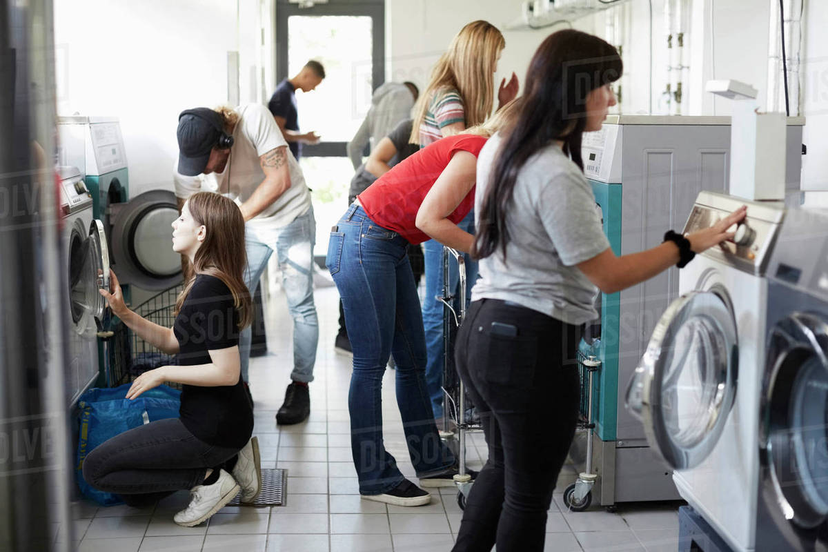 Multi-ethnic university students doing laundry at laundromat - Royalty ...