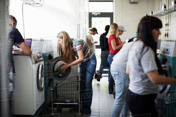 Multi-ethnic university students using washing machines in laundromat ...