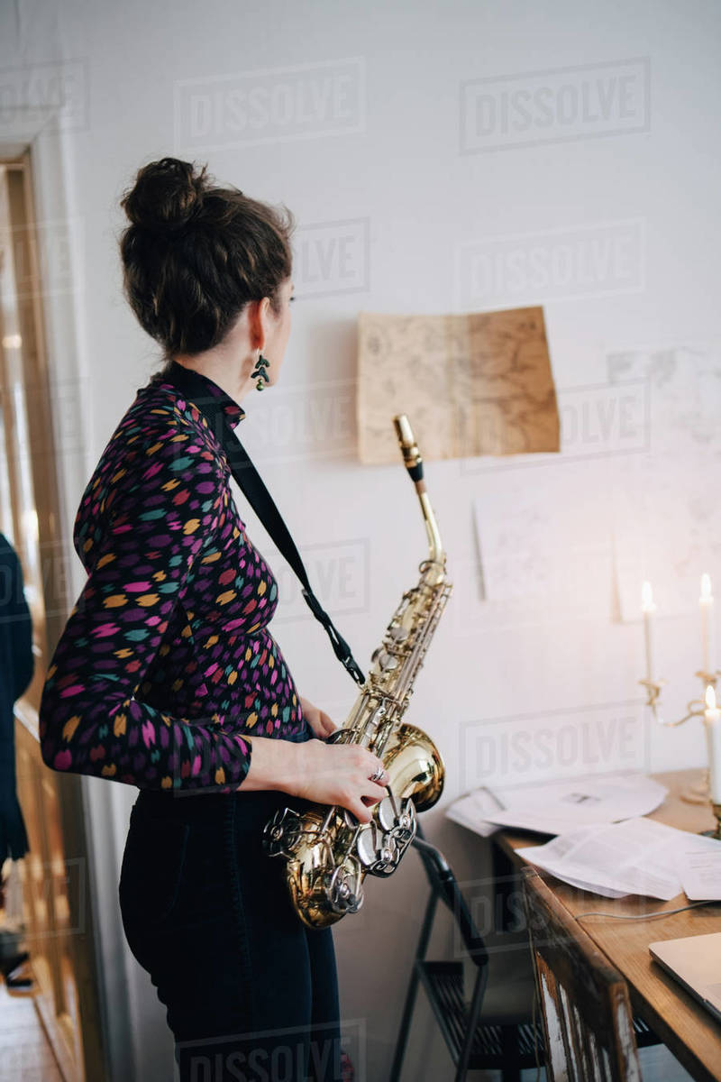 Side view of woman playing saxophone while practicing at studio ...