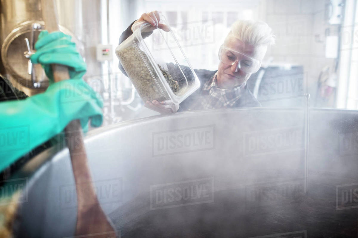 Female pouring ingredients in container while assisting coworker at ...