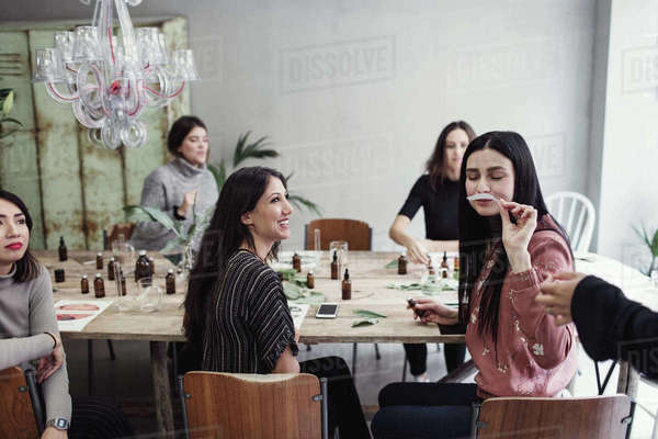 Woman smelling litmus strip while sitting amidst multi-ethnic ...