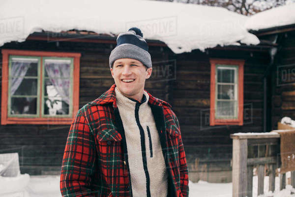 Smiling man standing against log cabin during winter - Royalty-free ...