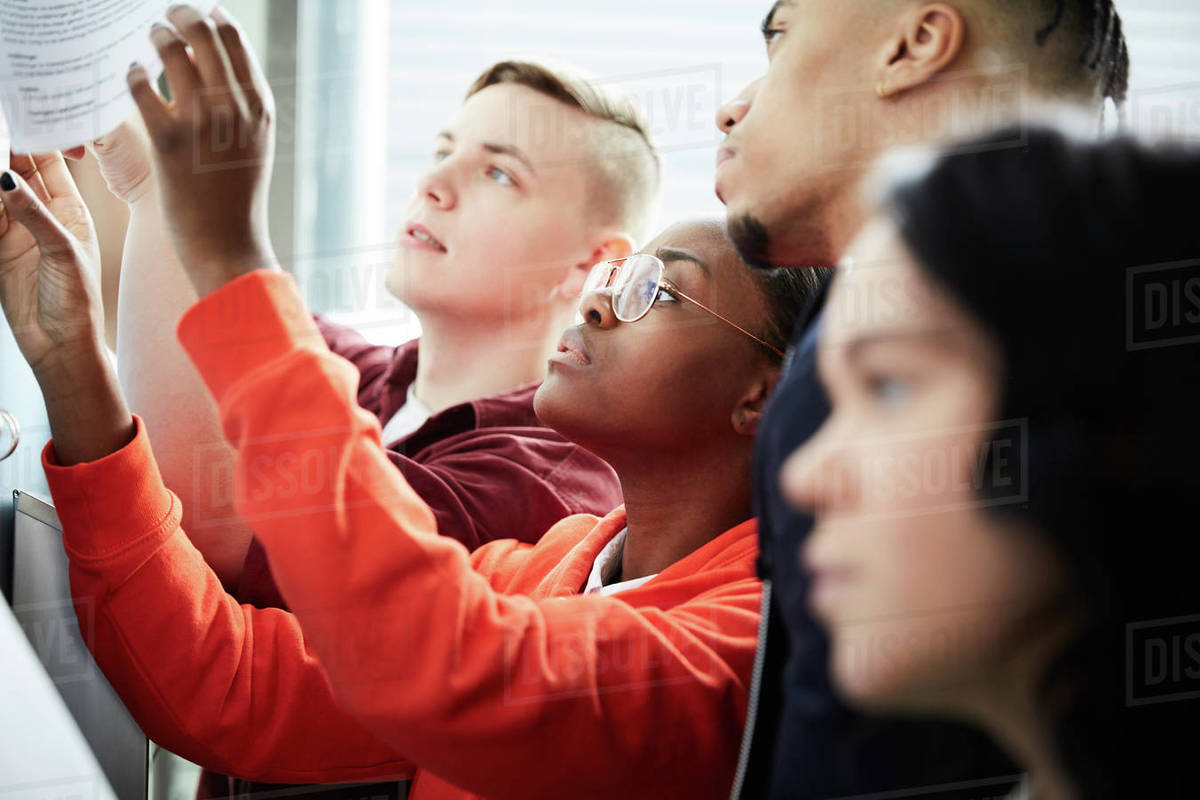 Male and female university students checking test results on bulletin ...