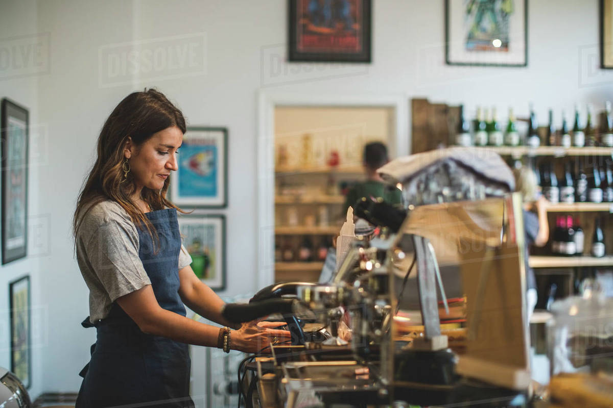 Side view of female sales clerk working at checkout counter in deli ...