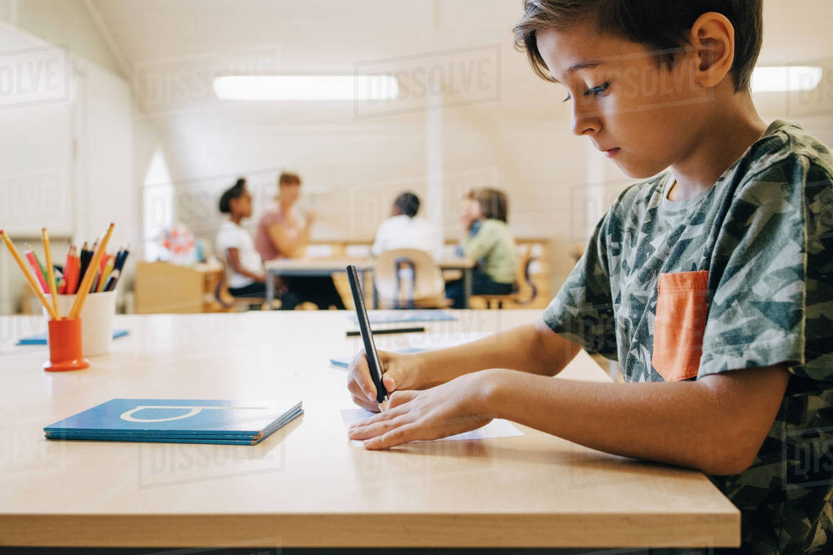 Close-up of boy concentrating while writing on paper at table - Stock ...