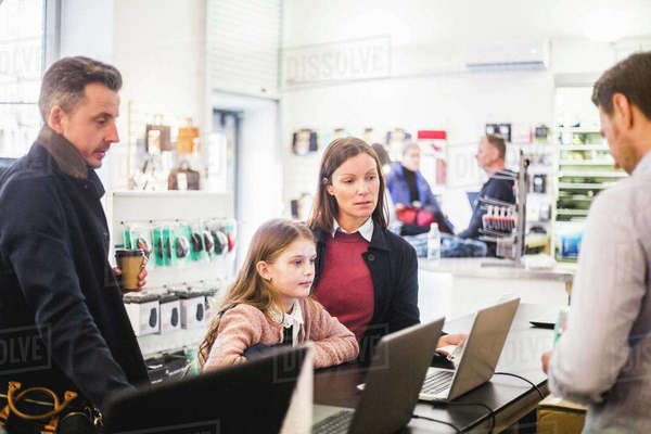 Family shopping for laptop in computer store - Stock Photo - Dissolve