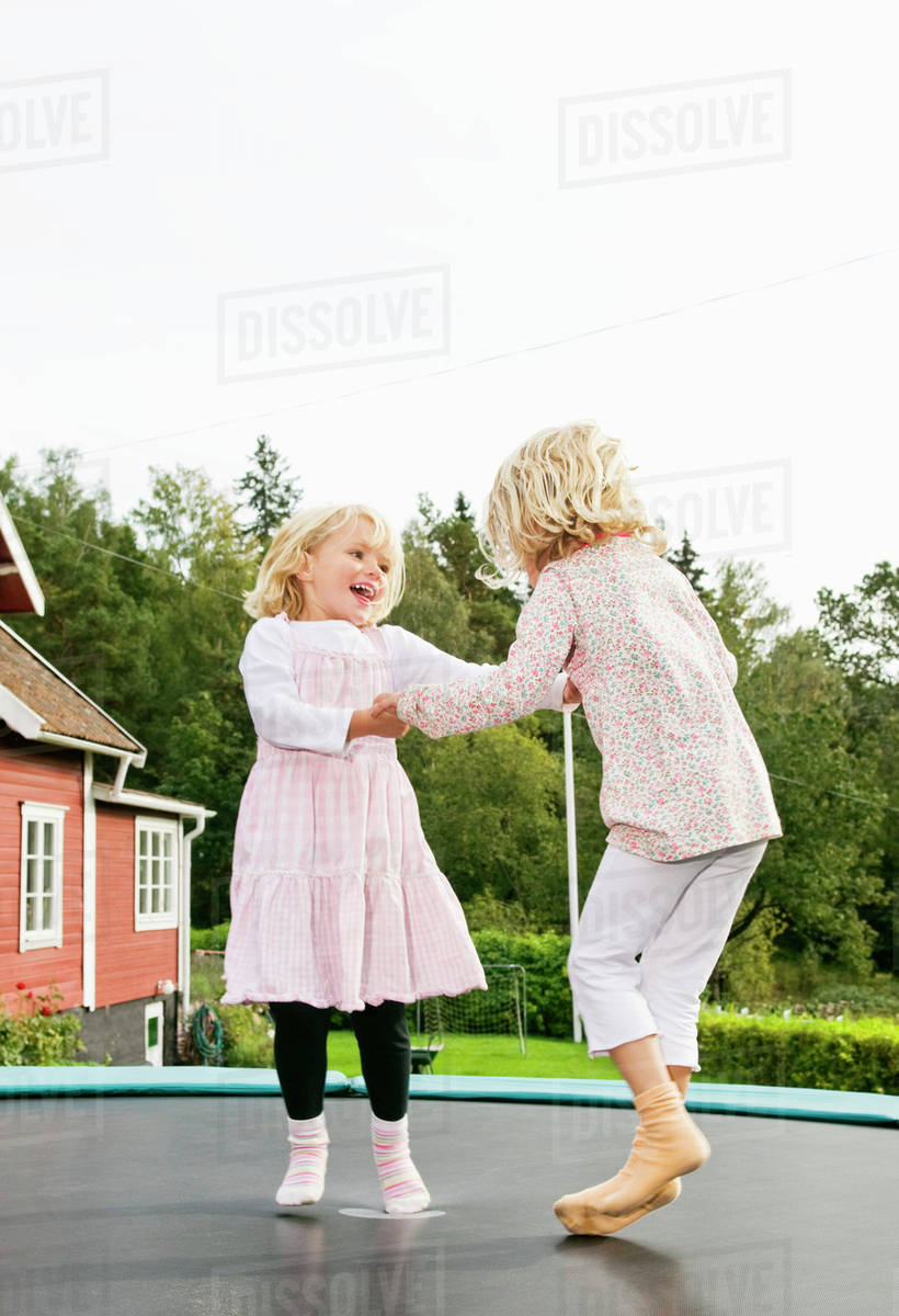Two sisters jumping on rebouncer - Royalty-free Stock Photo | Dissolve