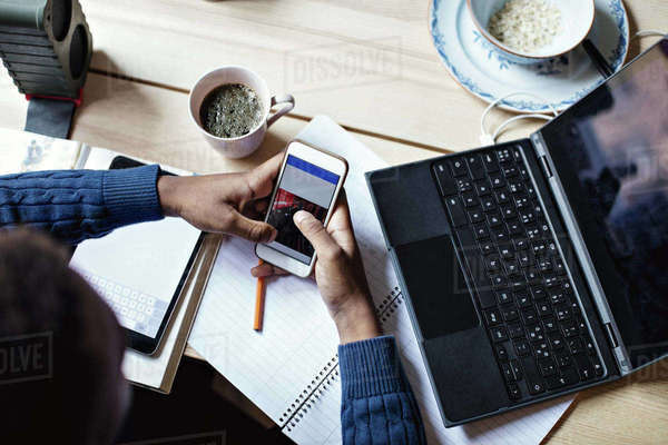 High angle view of teenage boy using mobile phone while studying on ...