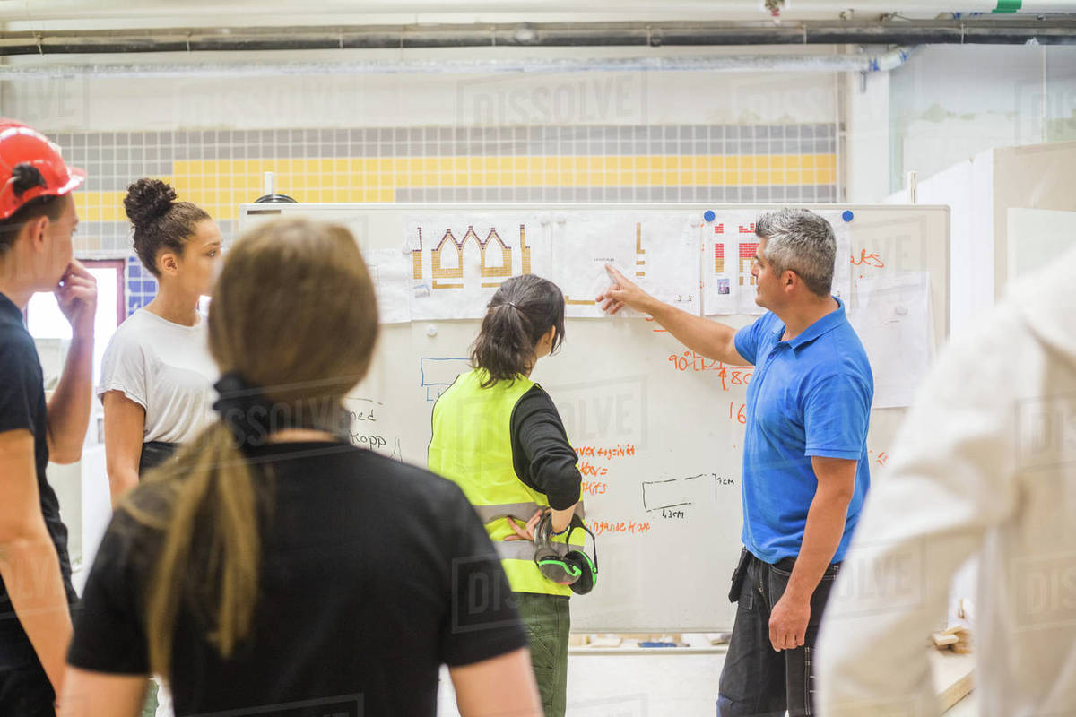 Male instructor teaching trainees while pointing over diagram on ...