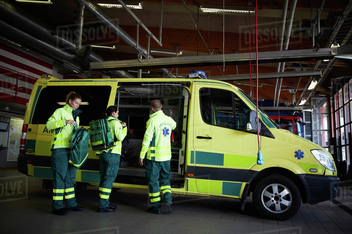 Full length of paramedics getting ready outside ambulance in parking ...