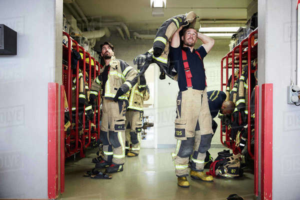 Firefighters wearing protective workwear in locker room while looking ...