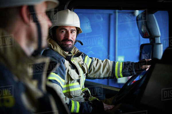 Firefighter looking at coworker while sitting in fire truck - Royalty ...
