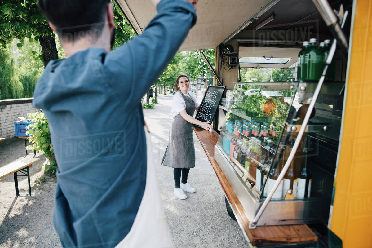 Female owner adjusting board on concession stand while male coworker ...
