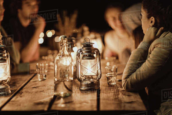 People sitting around illuminated table in restaurant at night ...