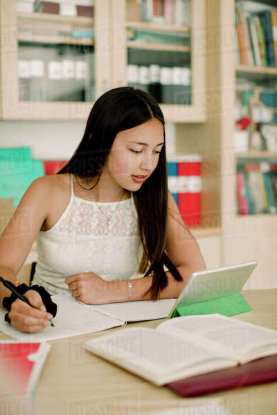 Teenage girl studying with digital tablet while sitting in classroom ...