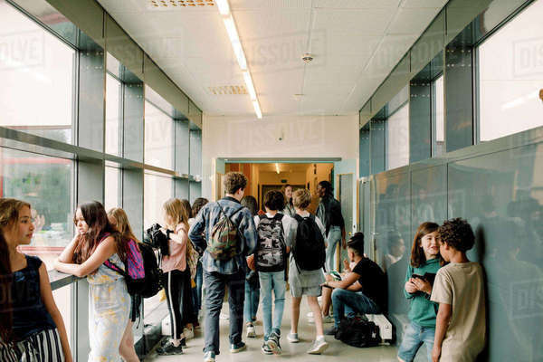 Rear view of students walking in school corridor during break - Stock ...