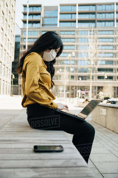 Profile of woman with face mask sitting outside working - Royalty-free ...